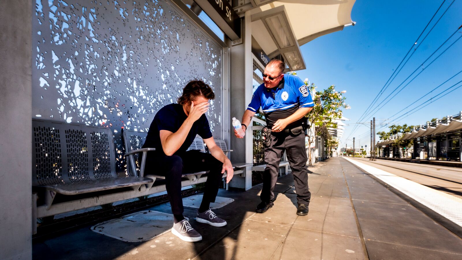 Security handing water to rider on platform