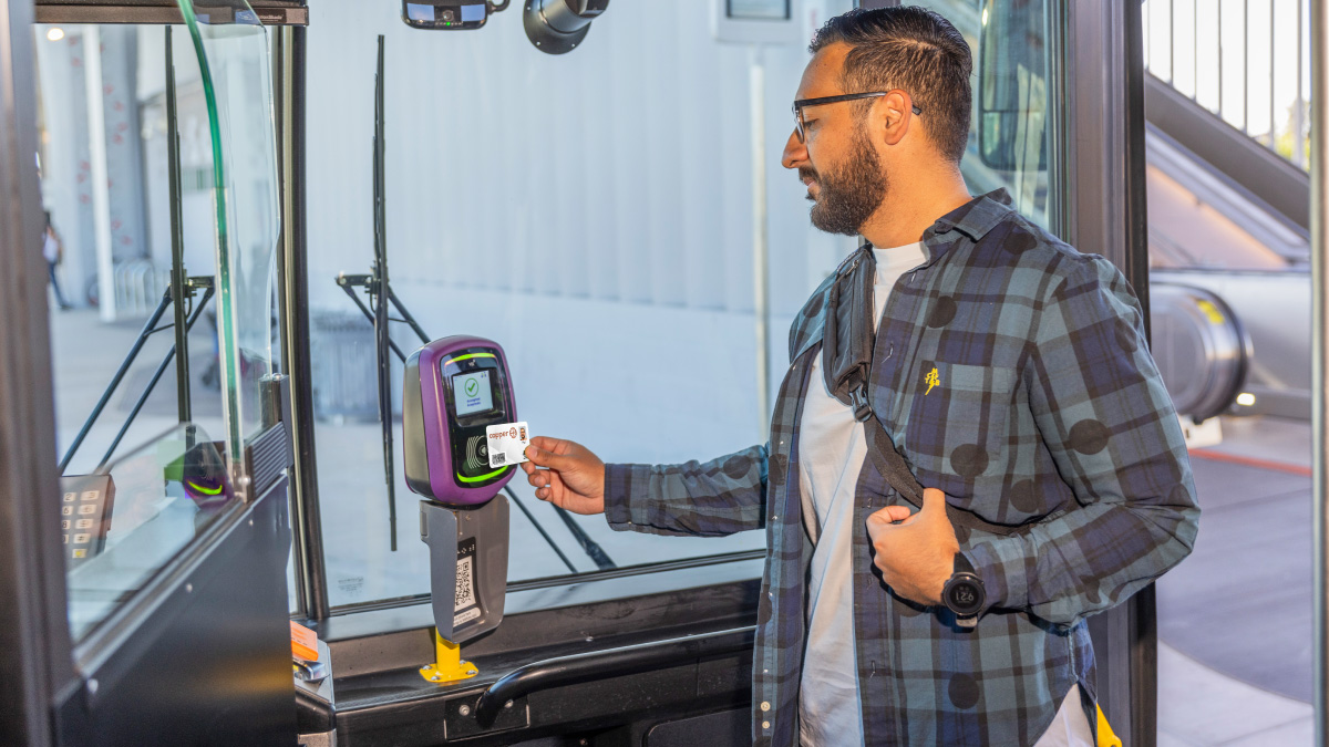 Young man tapping reduced fare Copper card to purple fare reader on the ...