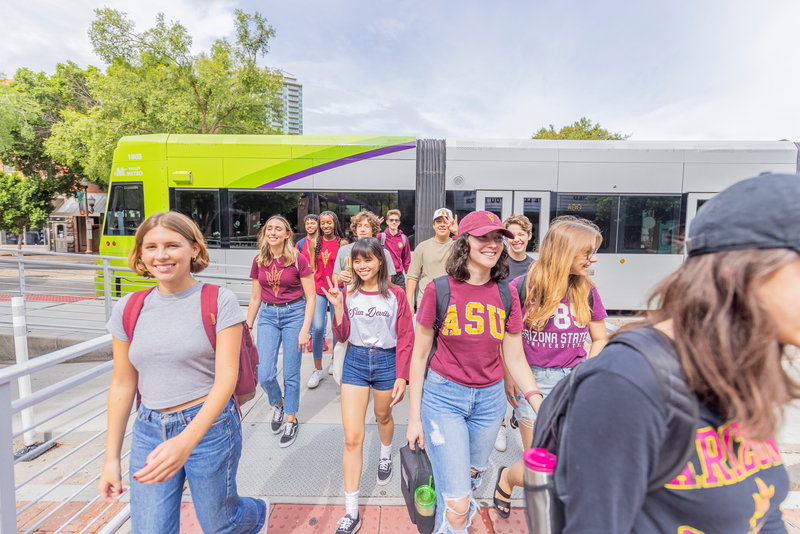 Smiling ASU students walking away from a streetcar