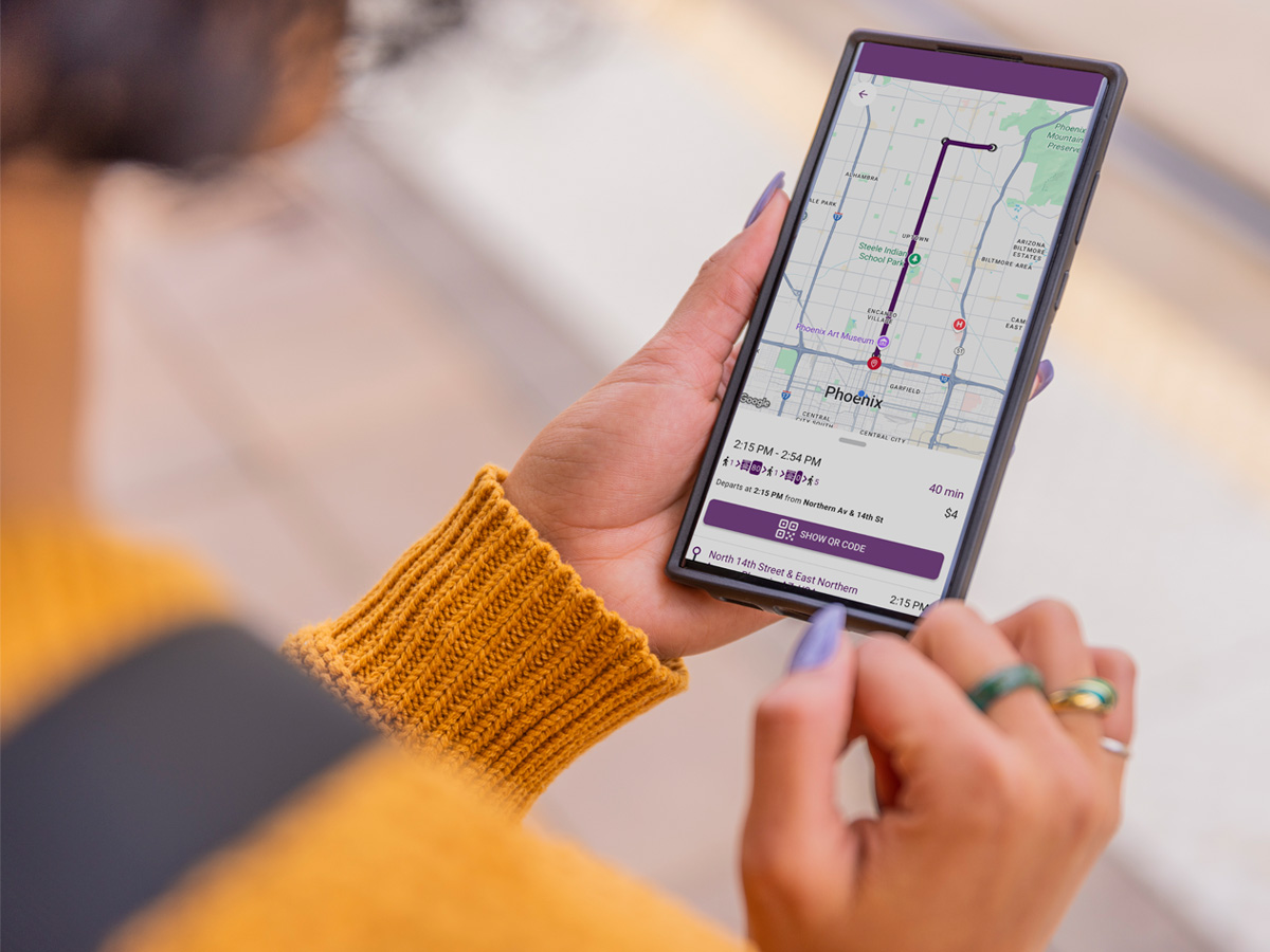 A woman holds a phone showing the Valley Metro app